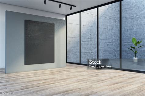 회색 파티션에 로고 또는 텍스트를 위한 장소가 있는 빈 검은색 포스터와 유리 벽 뒤에 밝은 천장과 식물 배경이 있는 햇볕이 잘 드는 빈 프레젠테이션 홀의 나무 바닥 3d