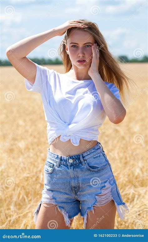 Young Blonde Woman In A White Shirt And Jeans Shorts Stock Image
