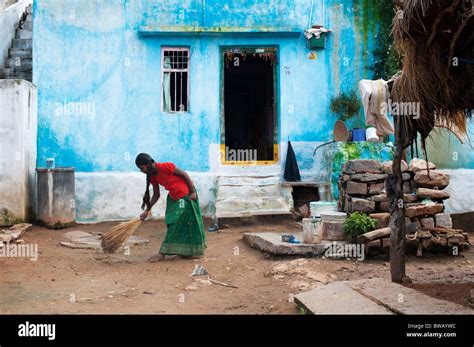Young Indian Girl Sweeping The Front Yard Of Her Home In A Rural Indian