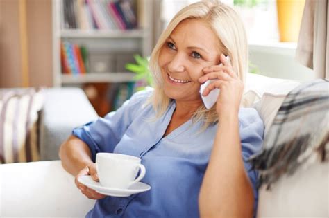 Entspannte reife frau genießt unterhaltung auf dem handy Kostenlose Foto