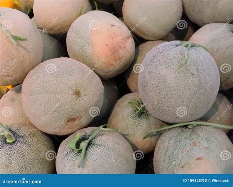 Group Of Small Green Yellow Melons With Stems Attached At A Market