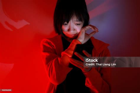 A Young Asian Girl Sits Indoors On The Floor Tears Streaming Down Her