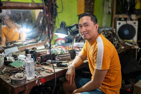 Portrait Of Electrical Engineer Sitting At Workstation In Tech Repair Shop Stock Image Image