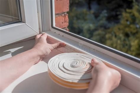 A Woman Glues A Sealing Rubber Tape On A Window In A Living Room Stock