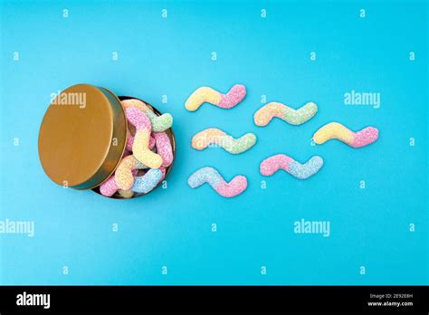 Sugar Coated Jelly Worms Crawling Out Of A Round Tin Box On A Blue