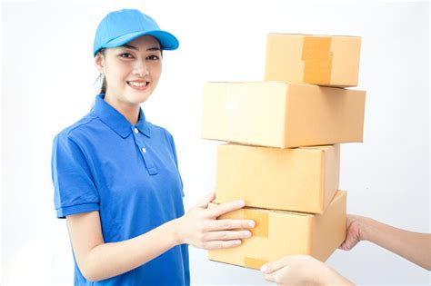 젊은 아시아 여자 유니폼에 배달 서비스 여자는 흰색 배경에 고립 된 매력적인 미소와 함께 고객에 게 상자를 보냅니다 나름에 대한