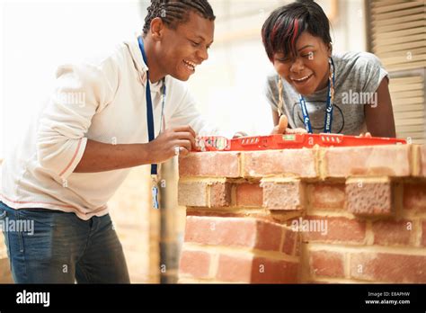 Two College Students Using Spirit Level In Bricklaying Workshop Stock