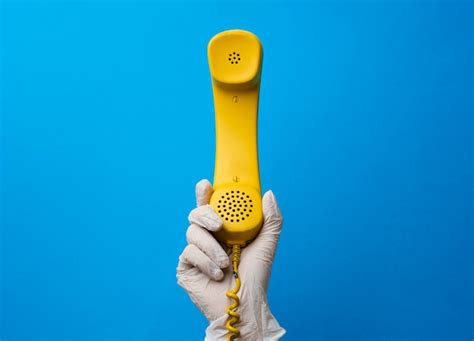 Premium Photo Female Hand In Medical Glove Holding Yellow Telephone