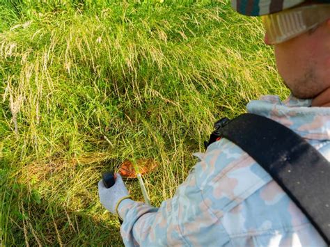 Close Up Of A Man Mowing High Grass With A Gasoline Trimmer View From