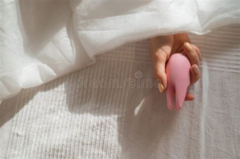 A Faceless Woman Lies In Bed Under A Blanket Holding A Clitoral
