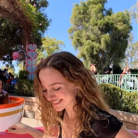 A Woman Sitting At A Table With A Bowl Of Food In Front Of Her And People Behind Her