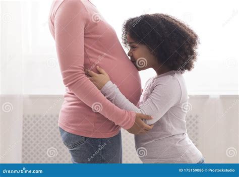 Adorable Little Afro Daughter Kissing Mother`s Pregnant Belly at Home Stock Photo - Image of ...