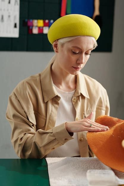 Premium Photo Young Female Designer Shaping New Felt Hat By Workplace