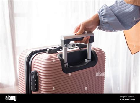 An Asian Womans Hand Pulls The Handle Of A Suitcase Isolated On A
