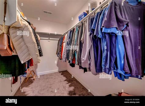 Walk In Closet Interior With Clothes Hanging On Metal Rods Below Wall