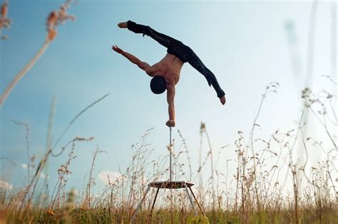 Premium Photo A Man Of Athletic Build Performs Complex Gymnastic Exercises In A Field