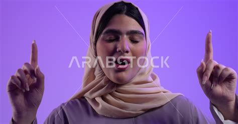 فتاة سعودية تنظر الى الكاميرا بإيماءات السرور، إشارات وحركات يدين تدل على هذا المكان هنا