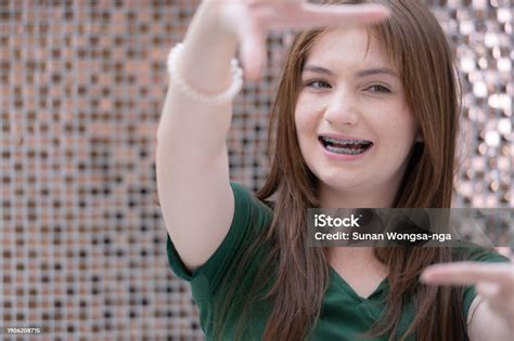 Young Woman With Braces On Her Teeth Making A Frame With Her Fingers