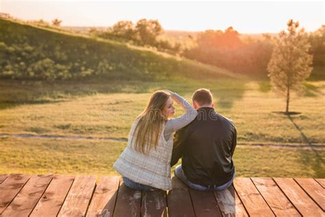Romantic Young Couple Enjoying Autumn Nature Sitting In A Close Embrace