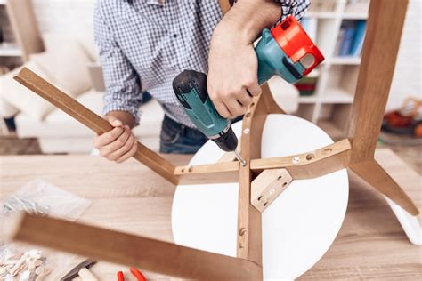 Premium Photo Furniture Assembler With Drill In Hands Repairs Chair