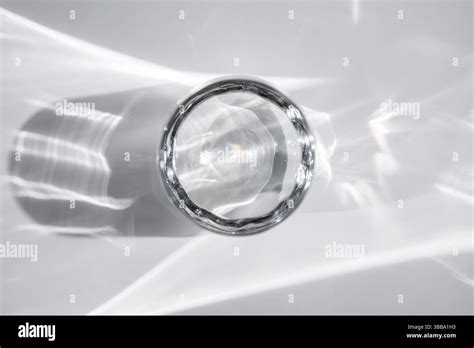 Glass Of Water Resting On A White Surface Creating An Elongated And