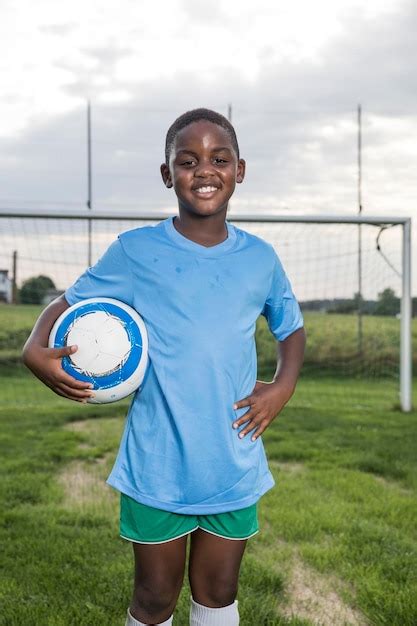 Portrait Dun Jeune Joueur De Football Souriant Tenant Le Ballon Sur Le