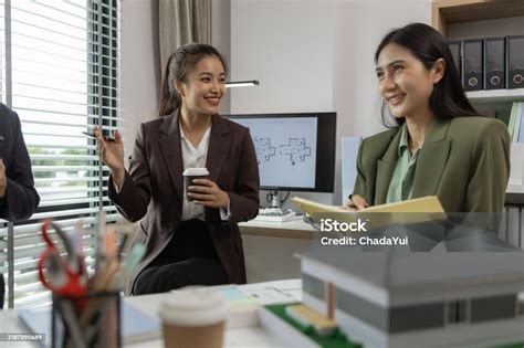 건축가는 사무실에서 엔지니어 및 계약자와 협력하여 첫 번째 초안 계획 책상 위의 청사진 작업장에서 함께 작업하는 청사진의