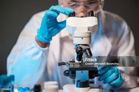 Asian Female Scientist Looking Under Microscope Analyzes Petri Dish