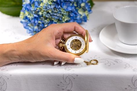 Premium Photo Close Up Of Woman Holding Pocket Watch On Table