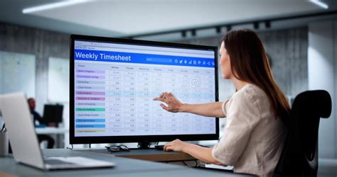 Woman In Office Signs Weekly Payroll Time Sheet For Overtime Stock