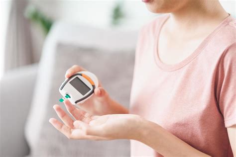 Asian Woman Checking Blood Sugar Level By Digital Glucose Meter