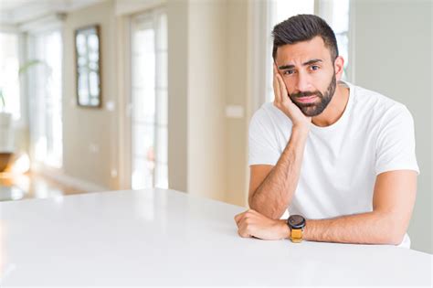 잘 생긴 히스패닉 남자 캐주얼 흰색 티셔츠 집에서 피곤 하 고 교차 된 팔과 우울증 문제로 지루 해 보이는 생각 T 셔츠에 대한 스톡 사진 및 기타 이미지 Istock