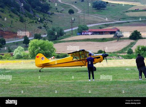 Yellow Plane Parked On Grass With People Around It On Grass In A Sunny
