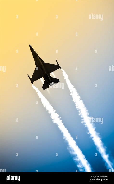 aerobatic military jet in a gradient sky leaving a smoke trail Stock Photo - Alamy