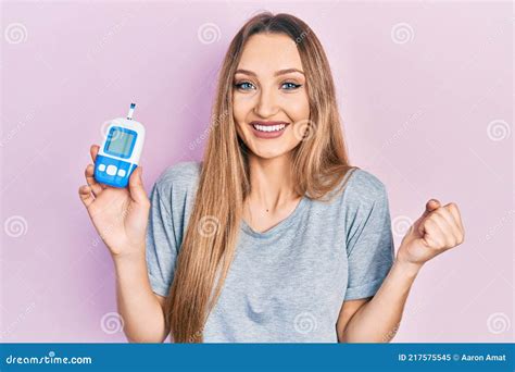 Young Blonde Girl Holding Glucometer Device Screaming Proud Celebrating Victory And Success