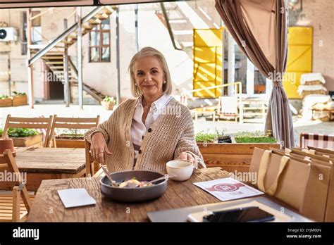 A Beautiful Gray Haired Woman Relaxes At An Outdoor Cafe Savoring Her