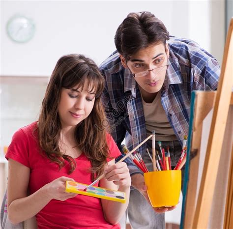 Photograph Of An Artist Coaching A Student In A Painting Class In A