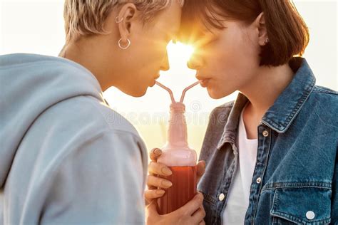 Happy Young Lesbian Couple Having Romantic Moment Drinking From One