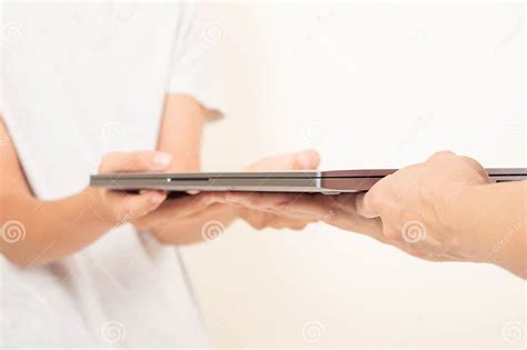 One Person Hands Holding Old Laptop Computer And Give It To Another