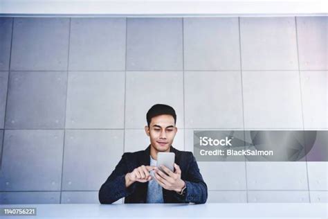 스마트 폰에서 작업 하는 행복 한 젊은 아시아 사업가 산업 다락방 직장에서 웃 고 책상에 앉 습니다 와이드 샷 긍정적인 감정 표현에 대한 스톡 사진 및 기타 이미지 Istock