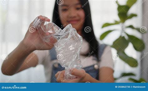 Asian Girl Crumples Plastic Water Bottles To Recycle Stock Image