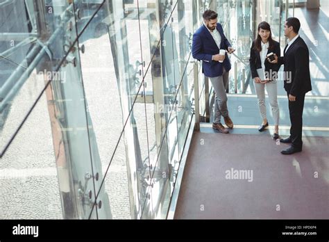 Smiling business executives interacting with each other outside platform Stock Photo - Alamy