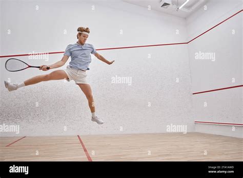 Motion Shot Funny Redhead Sportsman Holding Racquet And Jumping While