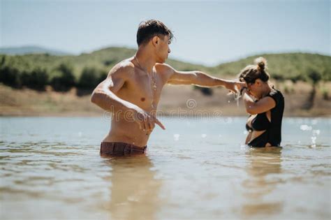 Young Couple Enjoying A Refreshing Swim In A Tranquil Lake On A Sunny