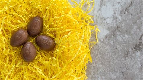 Four Chocolate Easter Eggs In Yellow Easter Grass On A Marble Counter