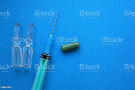 바늘주사기 약이 있는 바이알 정제는 파란색 배경에 놓여 있습니다 예방 접종 코로나 바이러스 의학 및 면역의 개념 바이러스 감염에 대한 예방 접종 공간을 복사합니다 단호하게