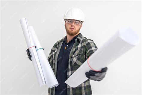 Ingeniero De Construcción Masculino En Mono Y Casco Sostiene Planos Y