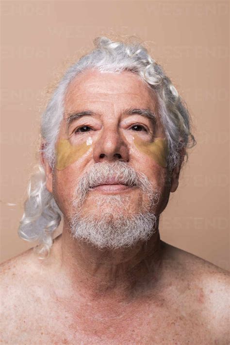 Shirtless Senior Man With Gray Hair And Eye Patch Against Beige