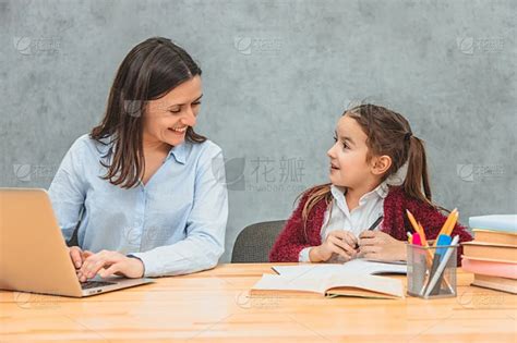 女孩在做家庭作业，而她的妈妈在厨房使用笔记本电脑素材 花瓣网