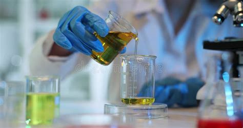 Assistant Pours Yellow Liquid Into Glass Beaker In Lab Stock Video